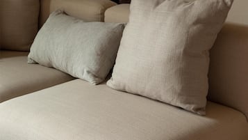 Um sofá bege com duas almofadas e estrutura de madeira.