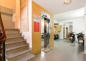 Uma escada leva a um espaço com uma porta, uma placa na parede e duas motocicletas estacionadas.
