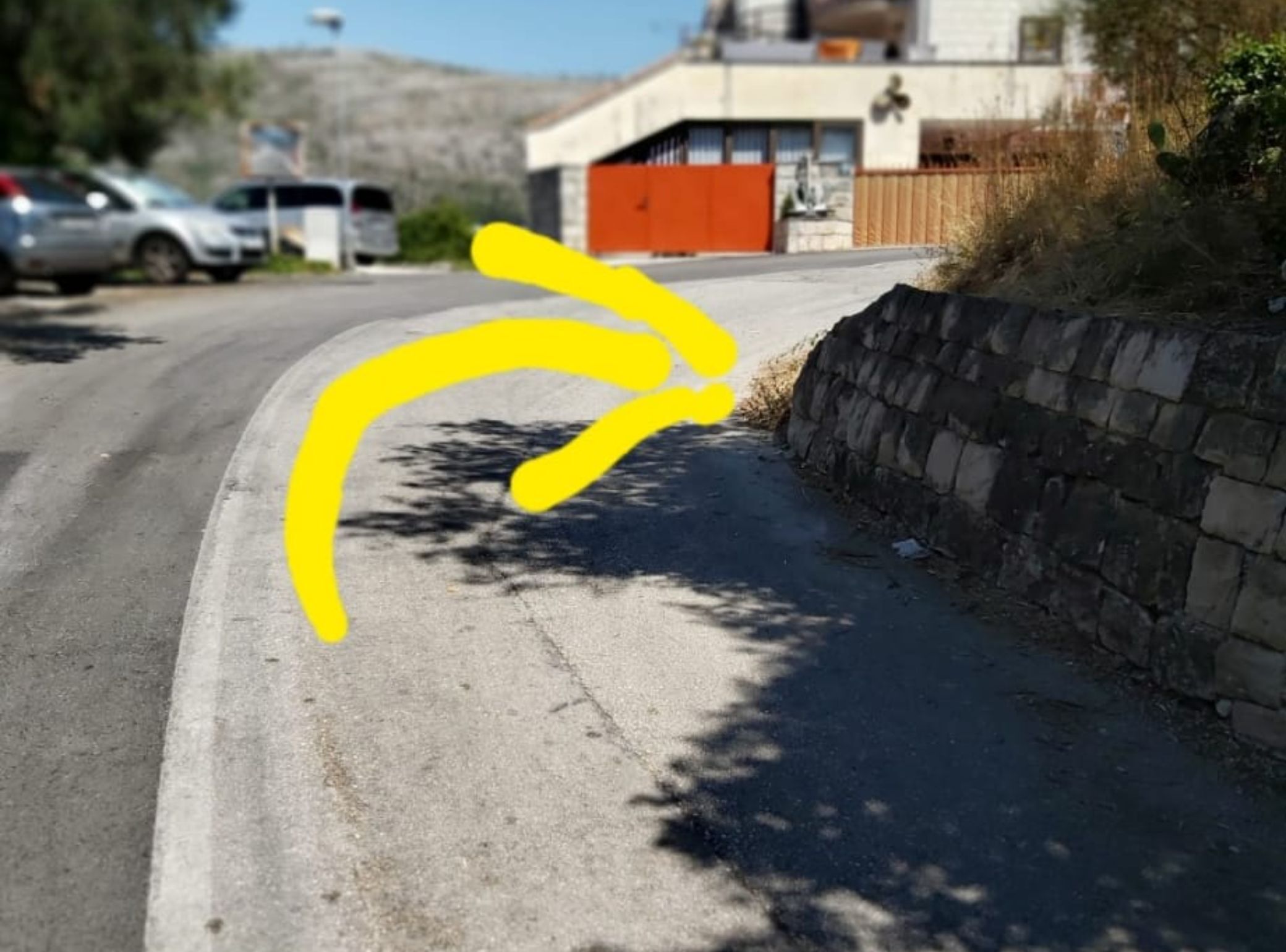 Uma estrada com uma seta amarela indicando uma curva.