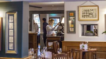 Interior de restaurante com mobiliário de madeira, obras de arte emolduradas nas paredes e um quadro de menu.