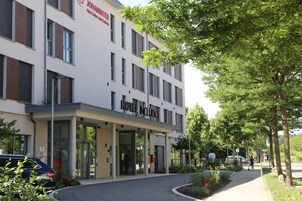 Um edifício de hotel moderno com uma placa que diz "Hotel Included", janelas grandes e entrada coberta.