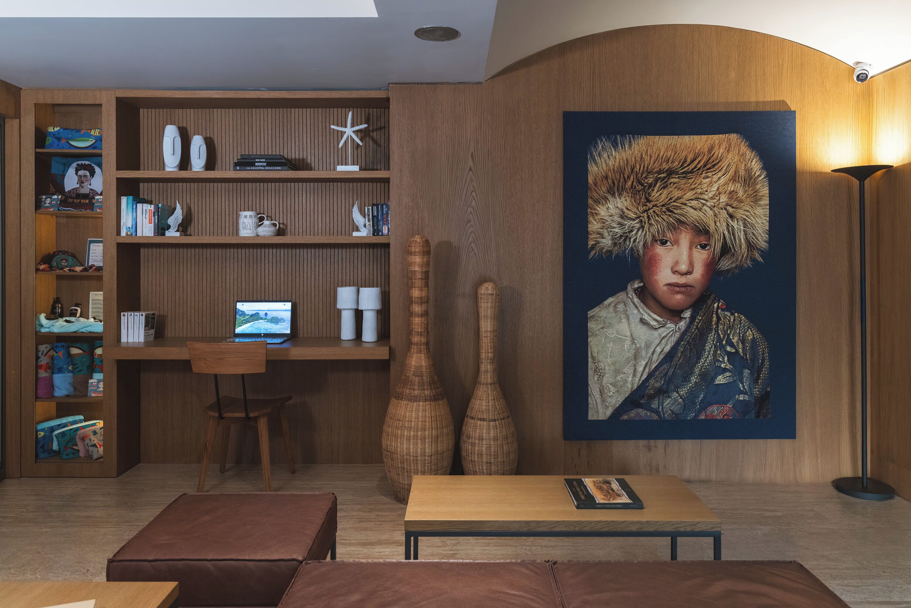 Uma sala de estar moderna com estante de madeira, escrivaninha e uma grande pintura.