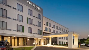 Hotel Courtyard by Marriott com design moderno, apresentando entrada coberta e área de estacionamento.