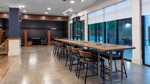 Uma sala de conferências moderna com uma mesa comprida, várias cadeiras e uma grande janela com vista para o exterior.