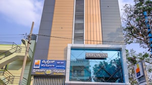 Um hotel moderno com design vertical marcante, fachada de vidro e placa indicando que é o DHRUVA INN.