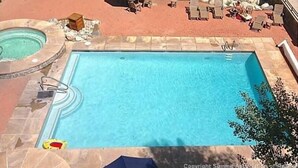 Piscina com hidromassagem, espreguiçadeiras e parede de pedra.