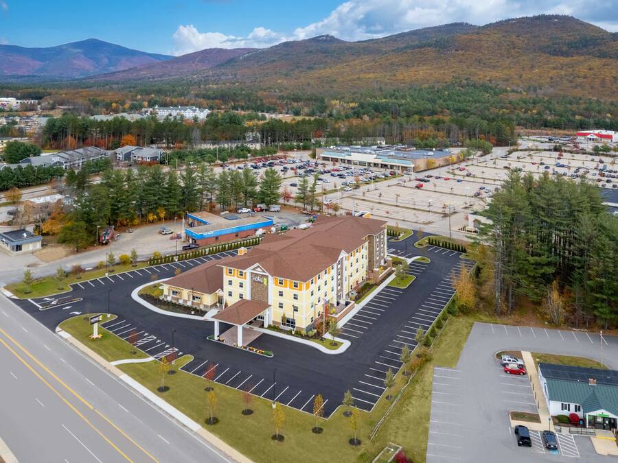 Um hotel com pátio central, estacionamento e vista para as montanhas ao redor.