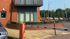 Um edifício com vários andares, fachada de tijolos, varandas múltiplas e entrada com portão.