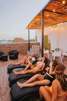 Área de estar no terraço, com espreguiçadeiras e um espaço de estar coberto.