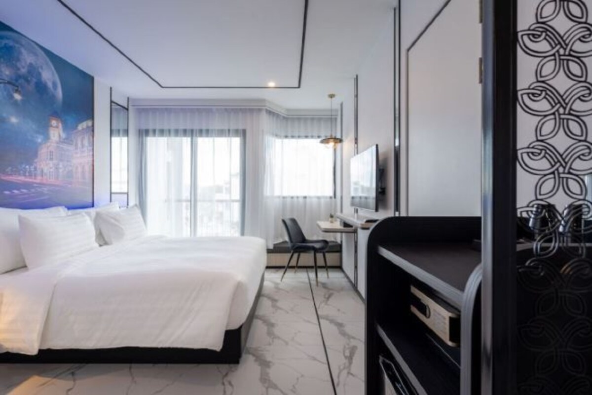 Quarto de hotel moderno com uma cama grande, uma escrivaninha e uma televisão.