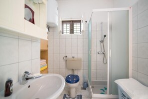 Casa de banho com lavatório, sanita e chuveiro.