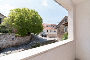 Um muro de pedra com uma árvore, uma rua e edifícios com telhados de telha vermelha.