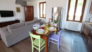 Sala de estar com sofá, mesa de jantar posta para dois e área de cozinha com geladeira e micro-ondas.