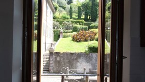 Visão através de uma porta para um jardim bem cuidado, com sebes aparadas e um muro de pedra.