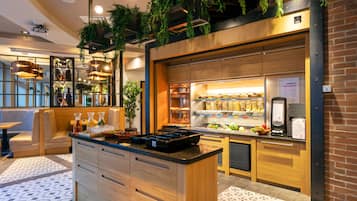 Uma cozinha moderna com armários de madeira, uma ilha central, plantas penduradas e um balcão de refeições rápidas.