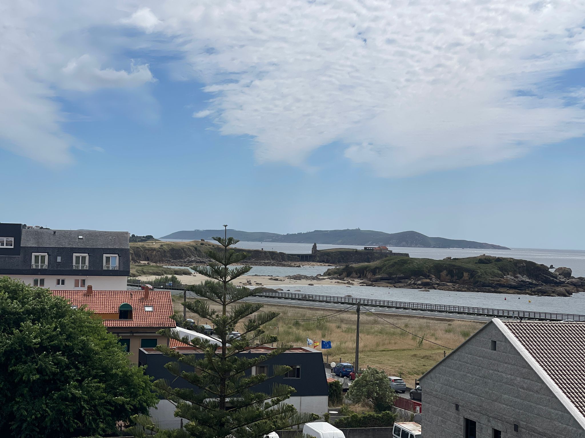 Vista costeira com edifícios, praia e uma ponte.