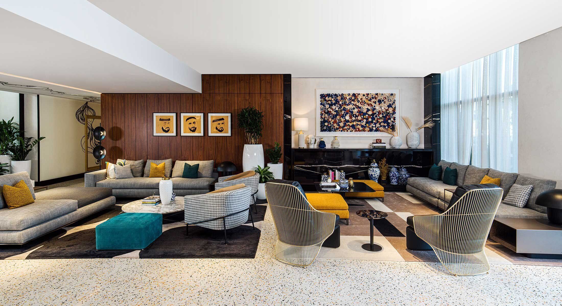 Uma sala de estar moderna com um sofá, uma mesa de centro e duas poltronas decorativas. Há uma lareira e um grande quadro abstrato na parede.