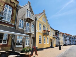 Uma fileira de edifícios coloridos com varandas e rua de calçamento.