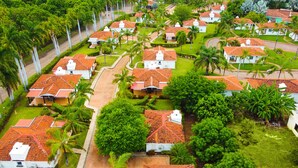 Vista aérea de um bairro residencial com casas de telhado vermelho, cercado por vegetação exuberante.