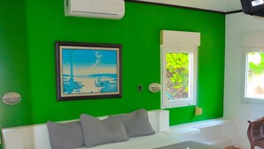 Quarto com uma cama grande, paredes verdes, janela com vista e ar condicionado.