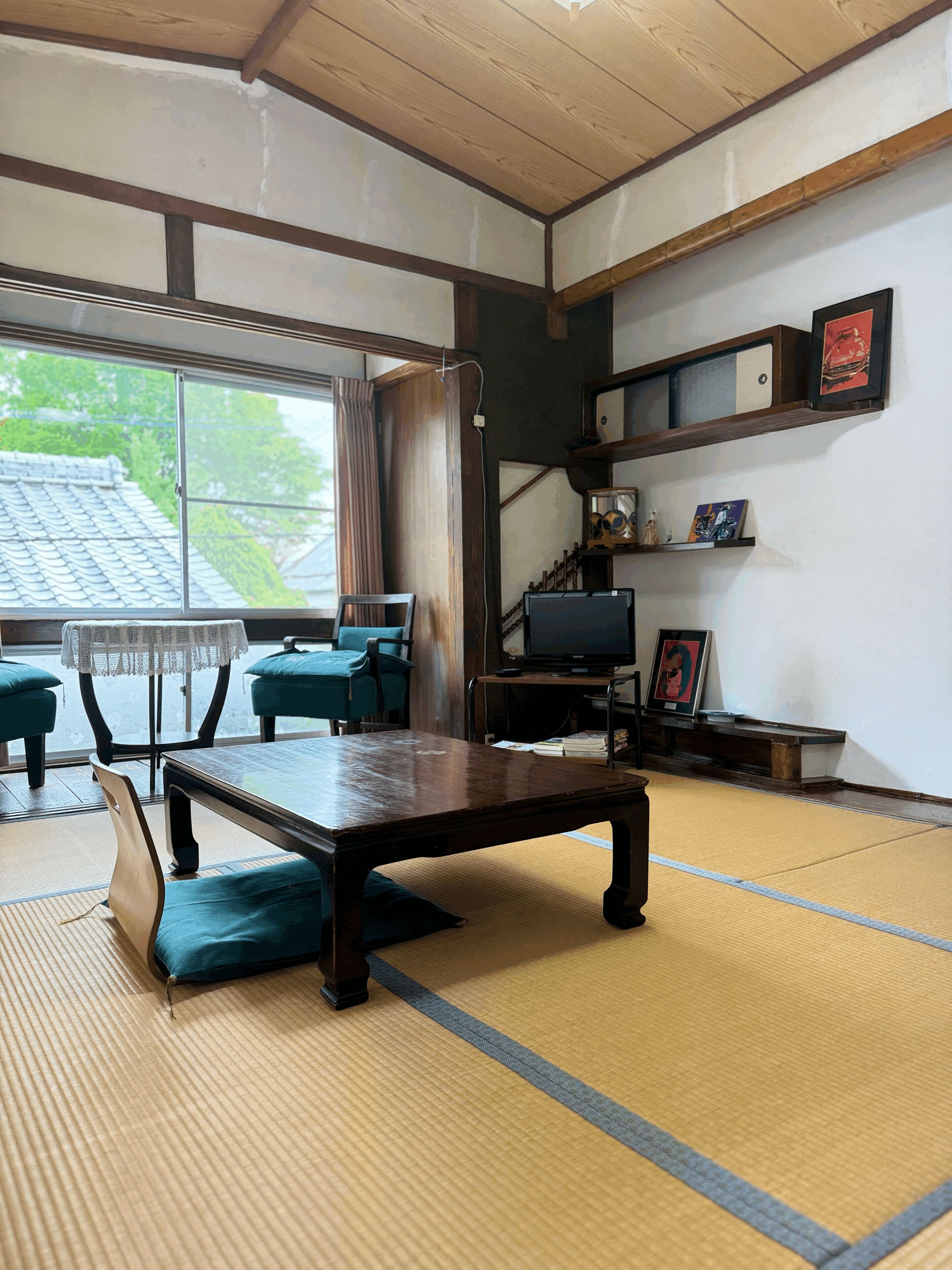 Um quarto japonês tradicional com tatames, uma mesa baixa e uma televisão.