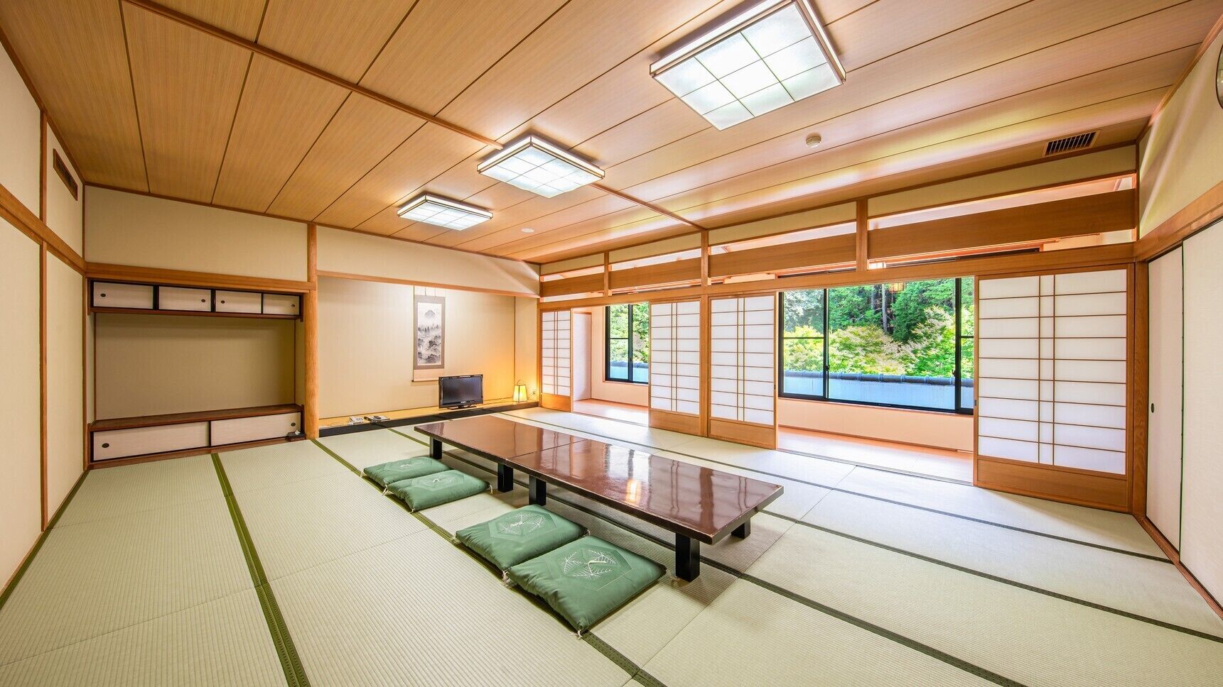 Um espaço com tatames, uma mesa baixa, portas deslizantes e uma televisão.