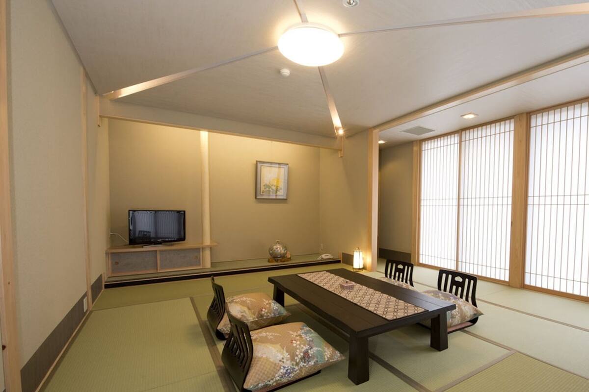 Um quarto japonês tradicional com tatames, uma mesa baixa e biombos shoji.