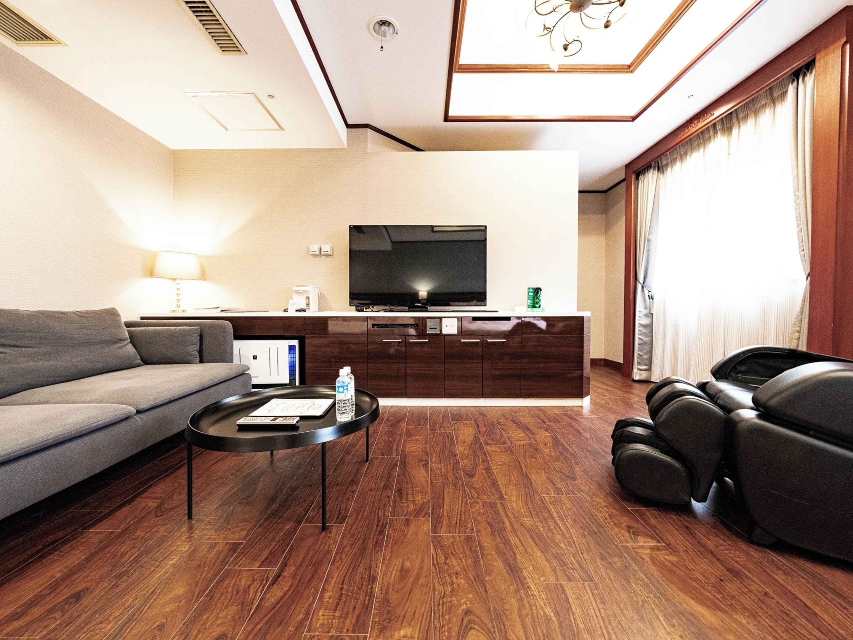 Uma sala de estar moderna com um sofá, uma mesa de centro, uma TV de tela plana e uma poltrona de massagem.