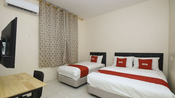 Quarto de hotel com duas camas, uma escrivaninha, televisão e ar condicionado.