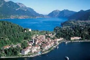 Uma vila costeira com edifícios ao longo da orla, cercada por montanhas e uma grande extensão de água.