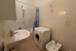 Casa de banho com lavatório, bidé, máquina de lavar e chuveiro.