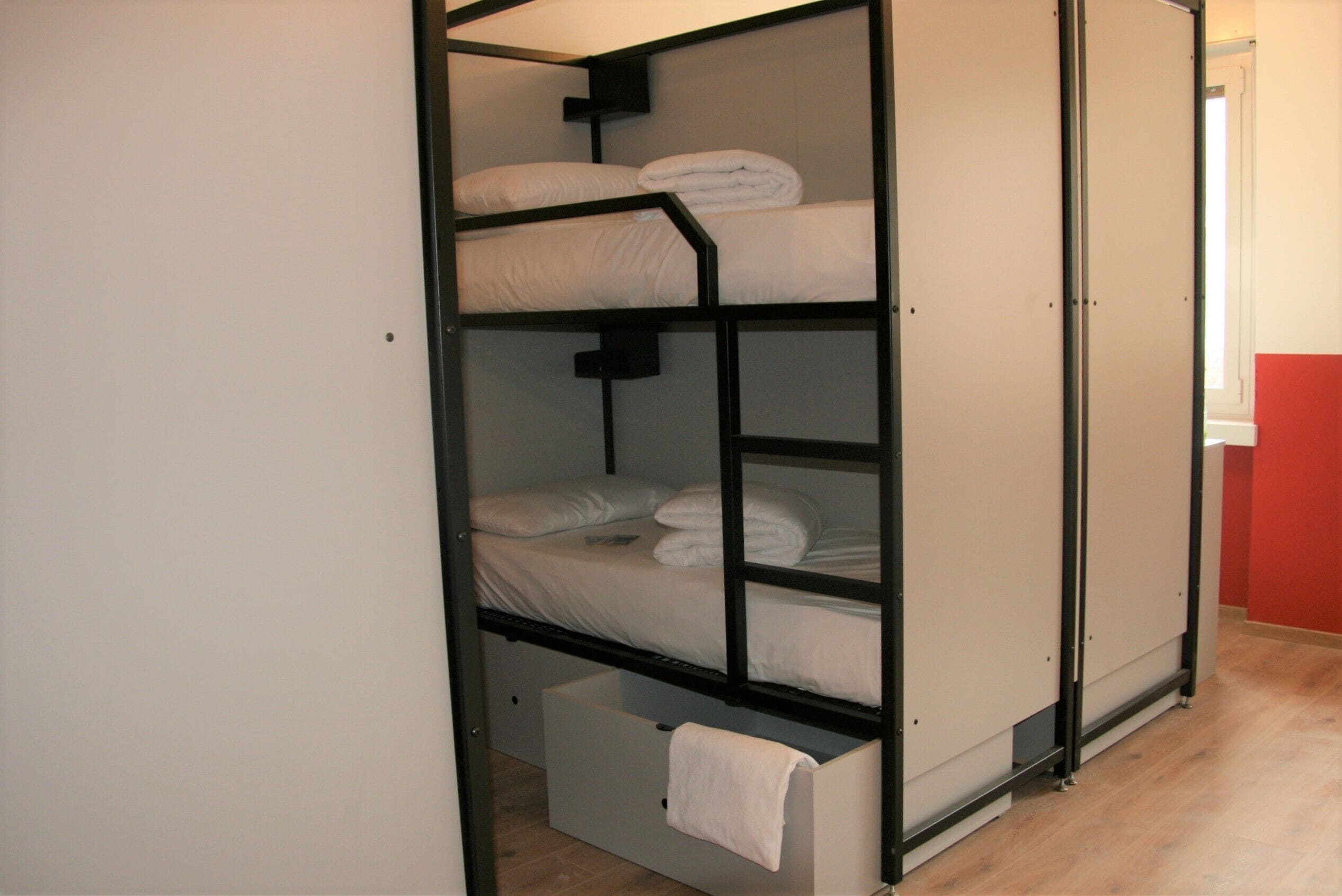 Uma cama de solteiro com roupa de cama branca e uma toalha pendurada na cama inferior.