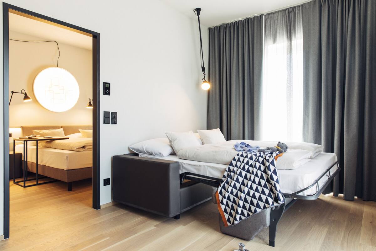 Quarto moderno com cama, mesa de cabeceira e luminária pendente.