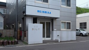 Um edifício com uma placa que diz 'UKISHIMA' e um carro estacionado.