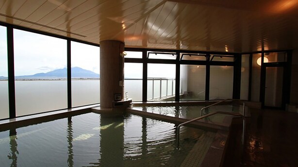 Uma piscina interior ampla com vista para um corpo d'água e montanhas.
