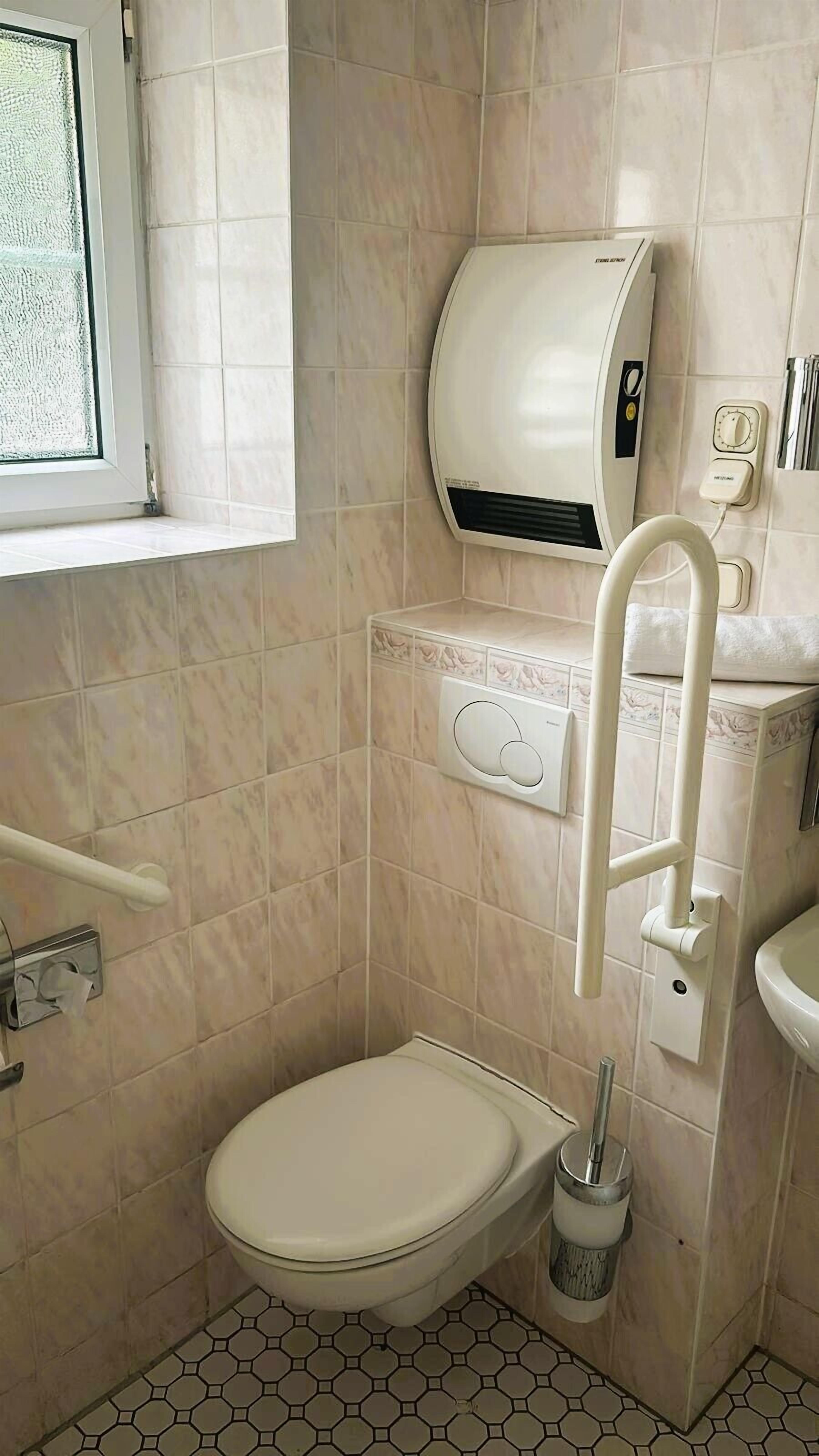 Um banheiro pequeno e moderno com vaso sanitário, bidê e secador de mãos.