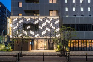 Um hotel moderno com fachada geométrica e entrada bem iluminada.