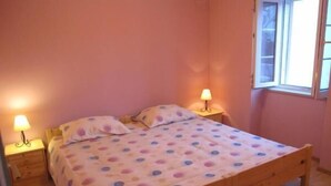Quarto com cama de madeira, duas mesas de cabeceira com luminárias e uma janela com vista.