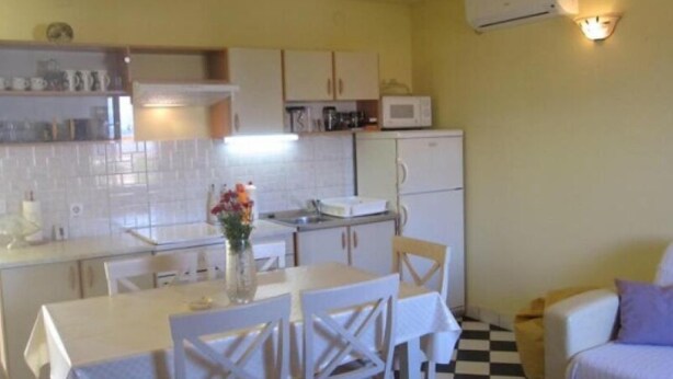 Uma cozinha compacta com armários brancos, micro-ondas e um espaço de refeições com mesa e cadeiras.