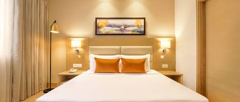Quarto de hotel com uma cama grande, duas mesas de cabeceira com luminárias, um quadro sobre a cama e uma cortina à esquerda.