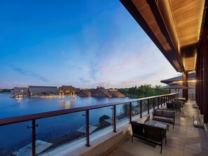 Um terraço à beira-mar com mesas ao ar livre e edifícios de estilo tradicional ao fundo.