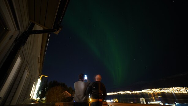 Duas pessoas observando o céu noturno de uma varanda com guarda-corpo.