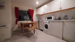 Uma cozinha compacta com máquina de lavar, micro-ondas e armários.