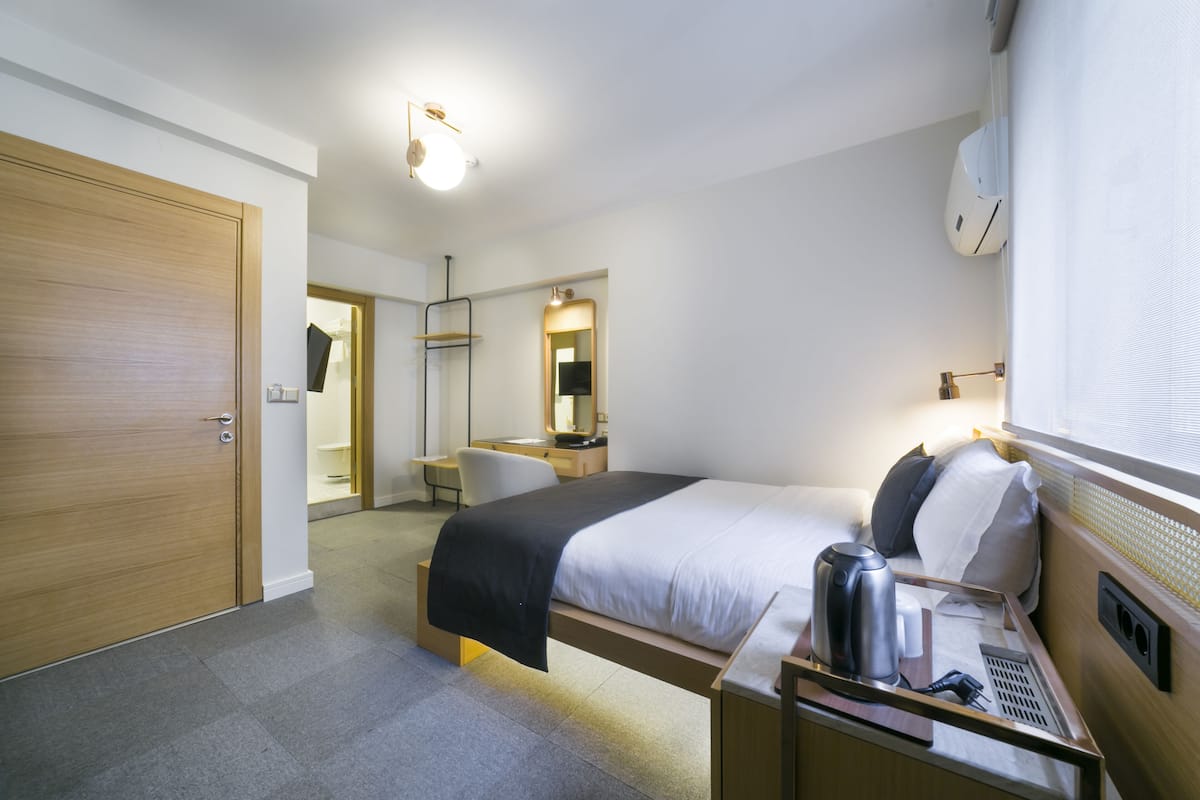 Quarto de hotel com cama, mesa de cabeceira e espelho.
