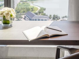 Uma mesa com um caderno aberto, uma caneta e um vaso de flores brancas.