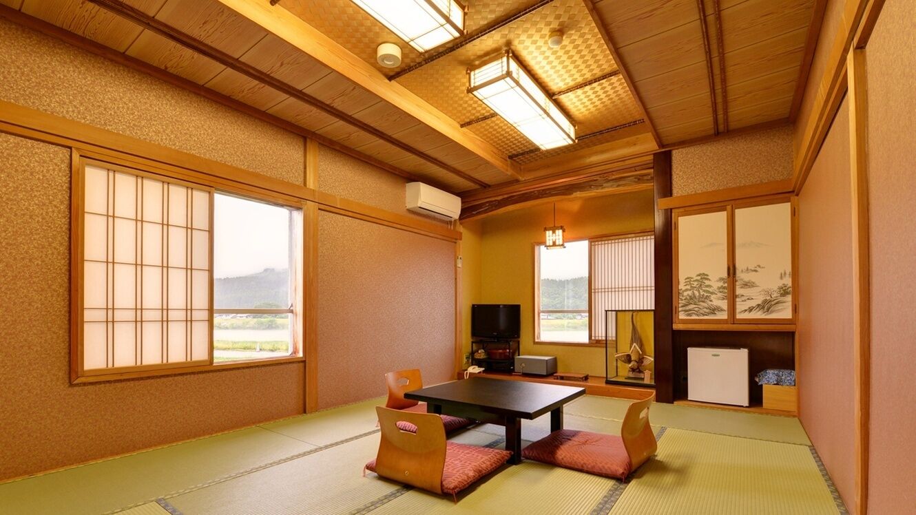 Um quarto japonês tradicional com tatames, uma mesa baixa, almofadas, portas deslizantes e vista para o exterior.