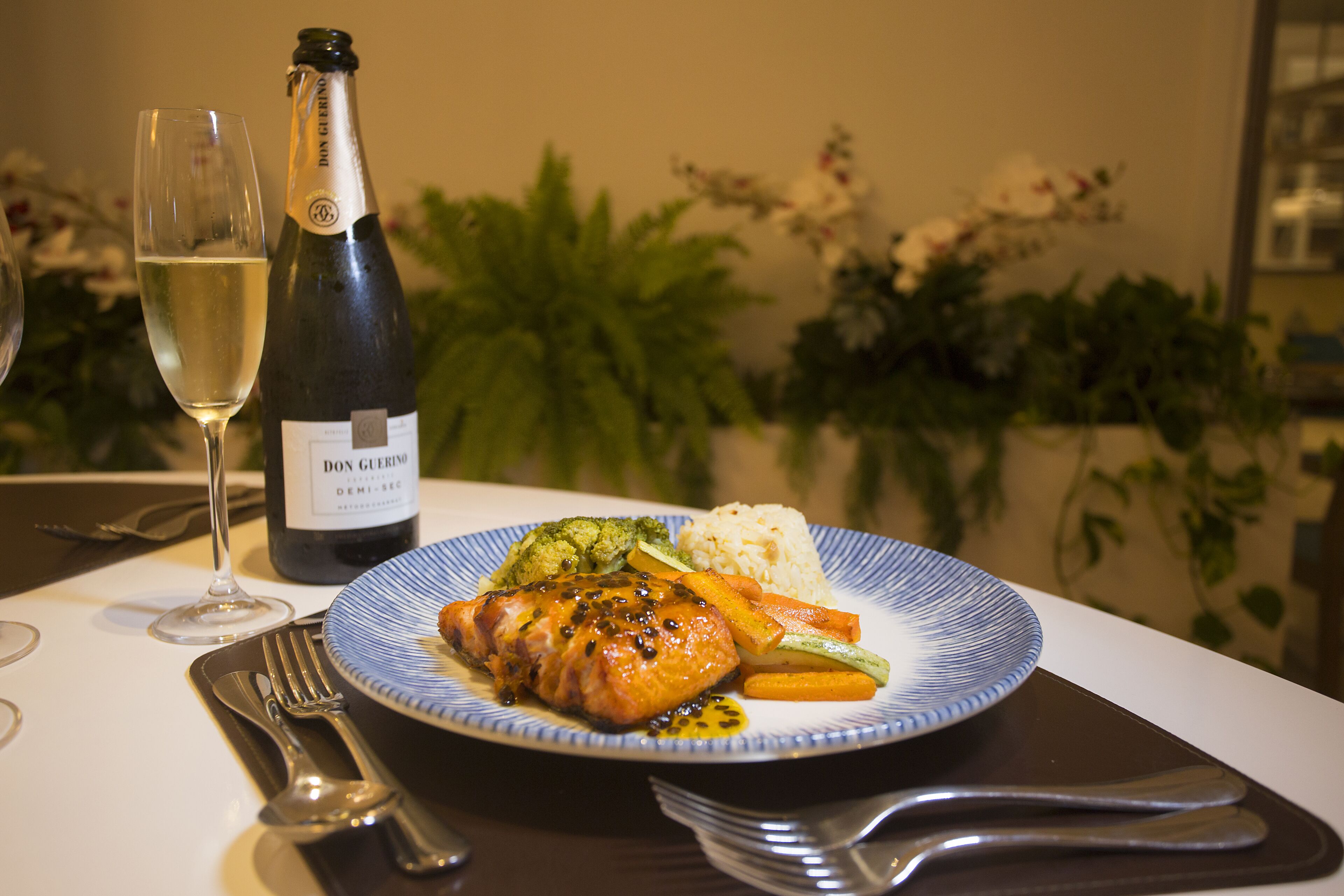 Prato de comida com uma garrafa de vinho e uma taça de vinho sobre uma mesa.