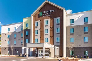 Edifício MainStay Suites com vários andares, entrada coberta e estacionamento.
