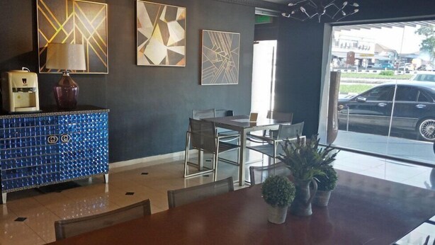 Um interior moderno com um armário de mosaico azul, arte abstrata na parede, uma área de refeições com cadeiras e plantas em vasos.