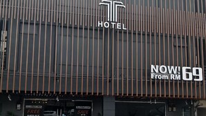 Hotel com fachada moderna, destacando ripas verticais de madeira e um logotipo em destaque.